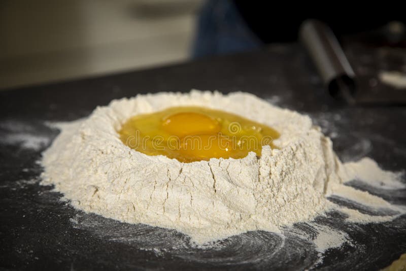 Eggs in Mound of Flour with a Hand and Fork Mixing Ready To Make Dough ...