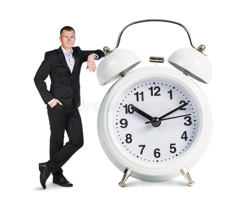 El Hombre De Negocios Se Coloca Cerca Del Despertador Blanco Grande ... El Hombre De Negocios Se Coloca Cerca Del Despertador Blanco Grande ...