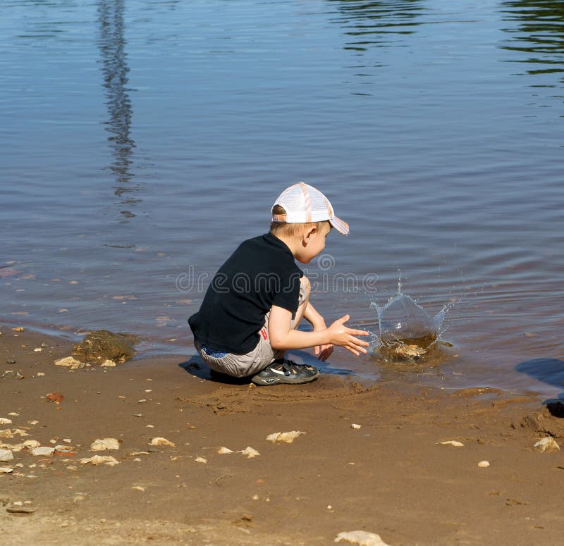 Un Niño Lanza Una Piedra Al Agua Imagen de archivo - Imagen de piedra ...