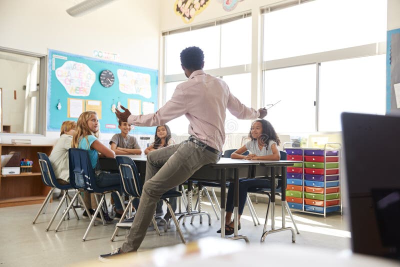 El Profesor De Sexo Masculino Con La Escuela Primaria Embroma En Clase De Escuela Imagen De