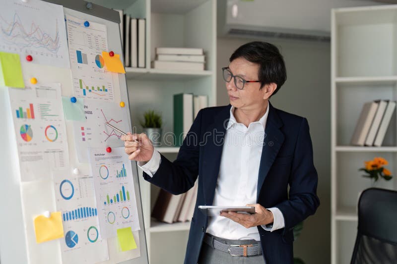 Elderly Businessman Presenting Data Analysis on a Board in a Modern ...