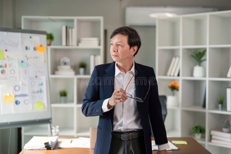Elderly Businessman Reflecting on His Work while Standing in a Modern ...