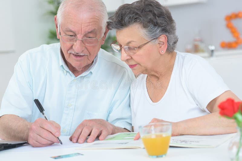 Elderly Couple Looking at Magazine and Taking Notes Stock Image - Image ...