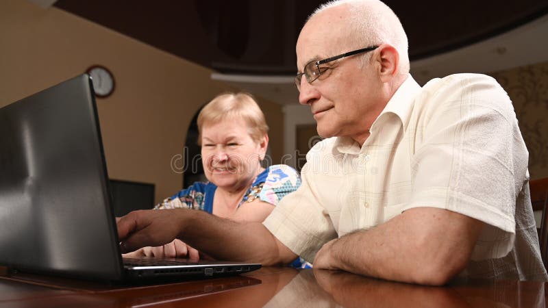 An Elderly Couple is Sitting at a Computer Looking for Information on ...