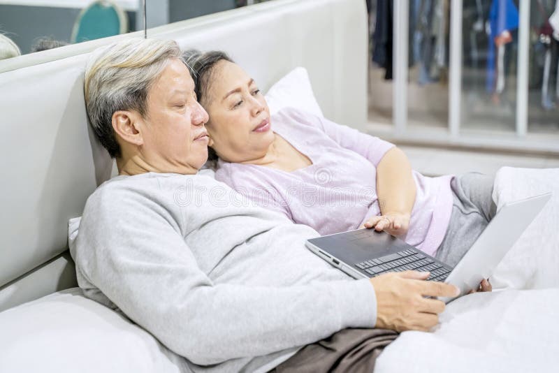Elderly Couple Using a Laptop Computer on the Bed Stock Photo - Image ...