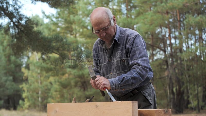 An Elderly Craftsman Skillfully Processes Wood Using a Chisel and a ...