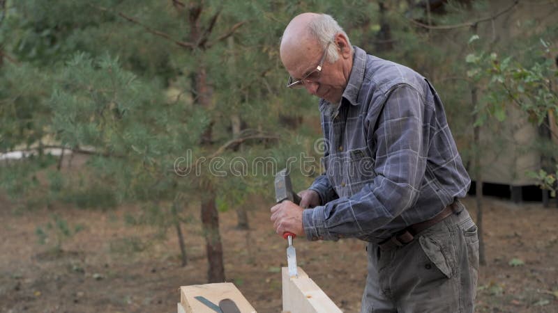 An Elderly Craftsman Skillfully Processes Wood Using a Chisel and a ...