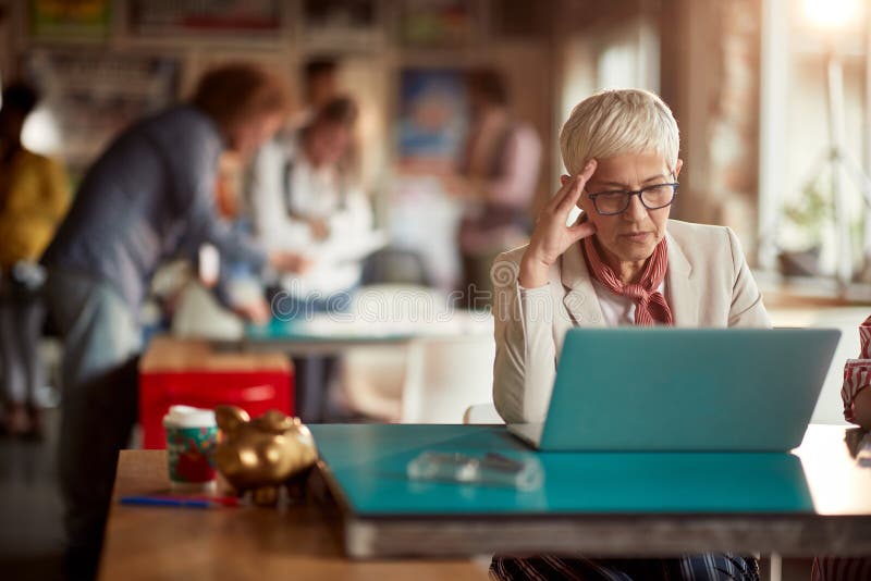An Elderly Female Office Employee is Focused on a Work on Laptop Stock ...
