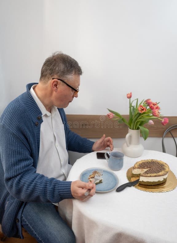 An Elderly Man Eating a Cake with Smartphone in His Kitchen Stock Image ...
