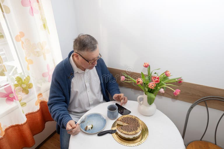 An Elderly Man Eating a Cake with Smartphone in His Kitchen Stock Image ...