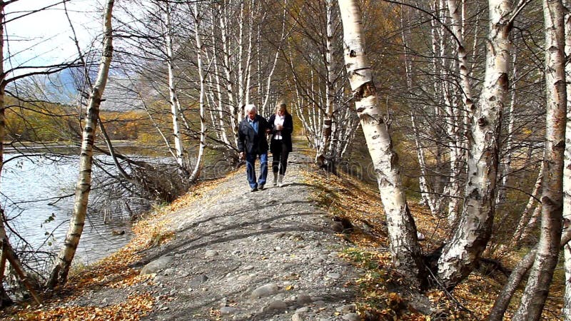 An Elderly Man with a Grown Daughter Walking on a Path in the Forest ...