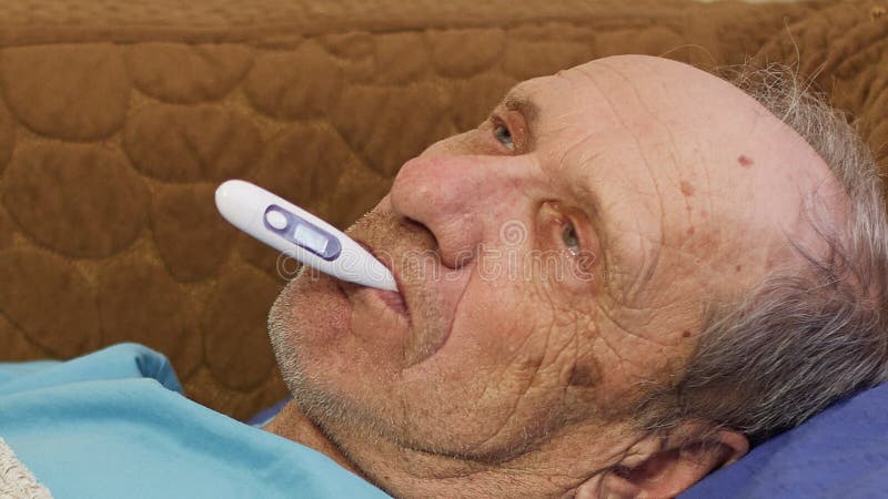 An Elderly Man with a High Temperature, Measuring the Temperature with ...