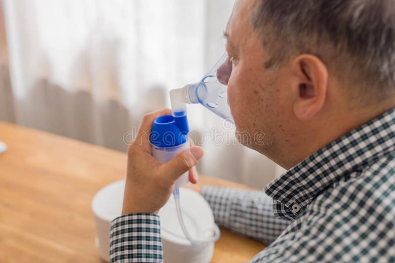 Elderly Man Sitting on a Table and Using a Nebulizer Mist at Home Stock ...