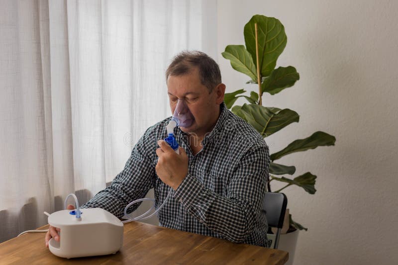 Elderly Man Sitting on a Table and Using a Nebulizer Mist at Home Stock ...