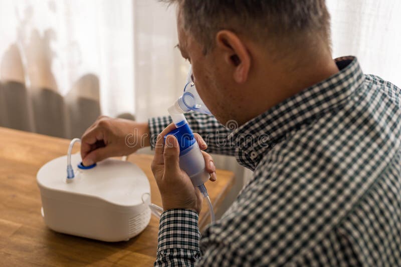 Elderly Man Sitting on a Table and Using a Nebulizer Mist at Home Stock ...