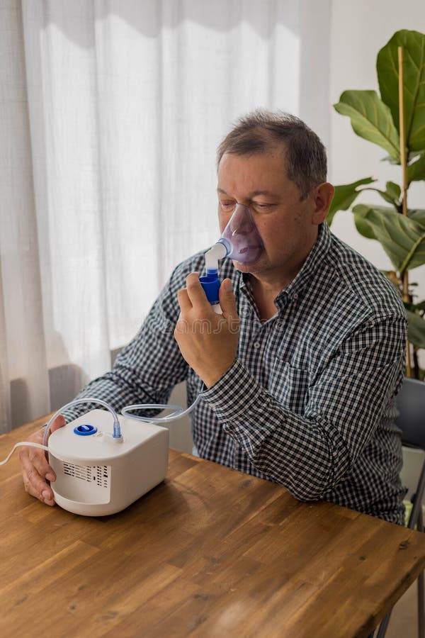 Elderly Man Sitting on a Table and Using a Nebulizer Mist at Home Stock ...