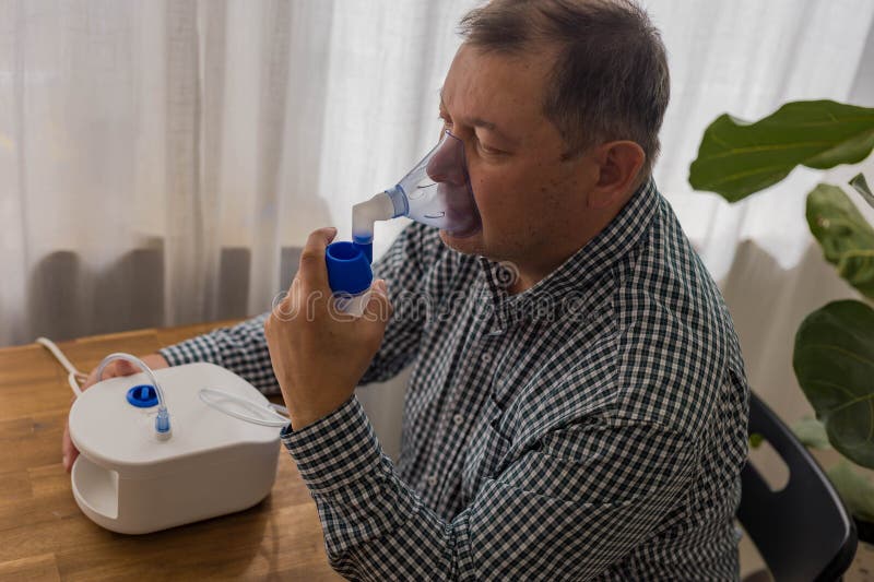 Elderly Man Sitting on a Table and Using a Nebulizer Mist at Home Stock ...