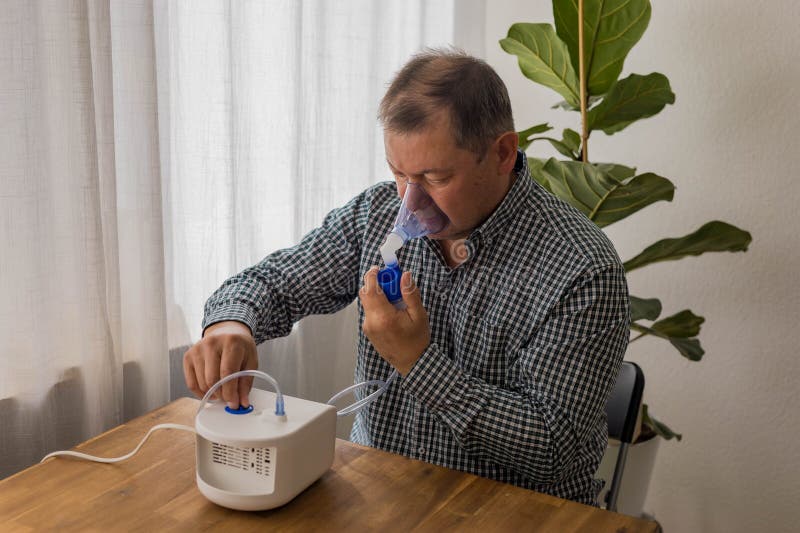 Elderly Man Sitting on a Table and Using a Nebulizer Mist at Home Stock ...