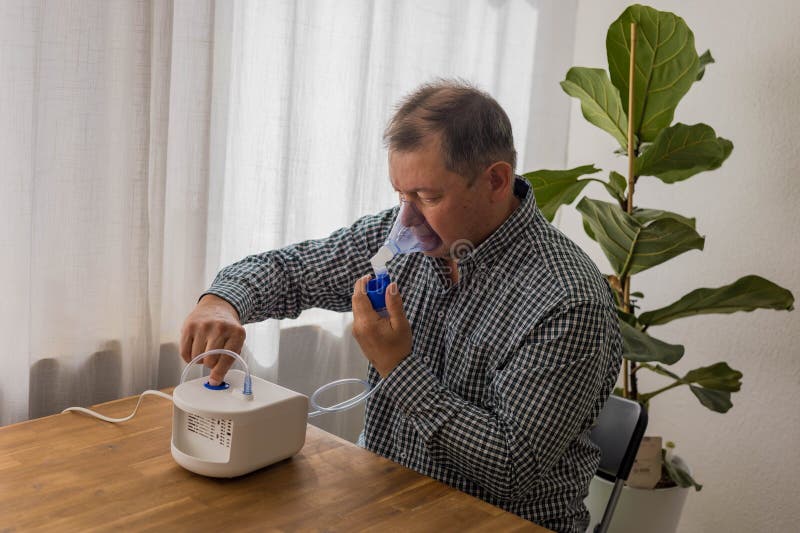 Elderly Man Sitting on a Table and Using a Nebulizer Mist at Home Stock ...