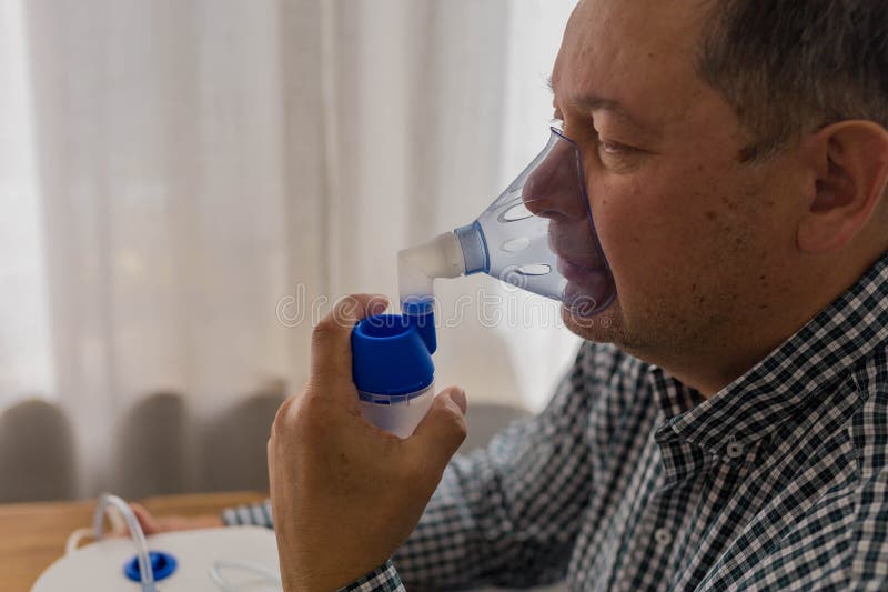 Elderly Man Sitting on a Table and Using a Nebulizer Mist at Home Stock ...