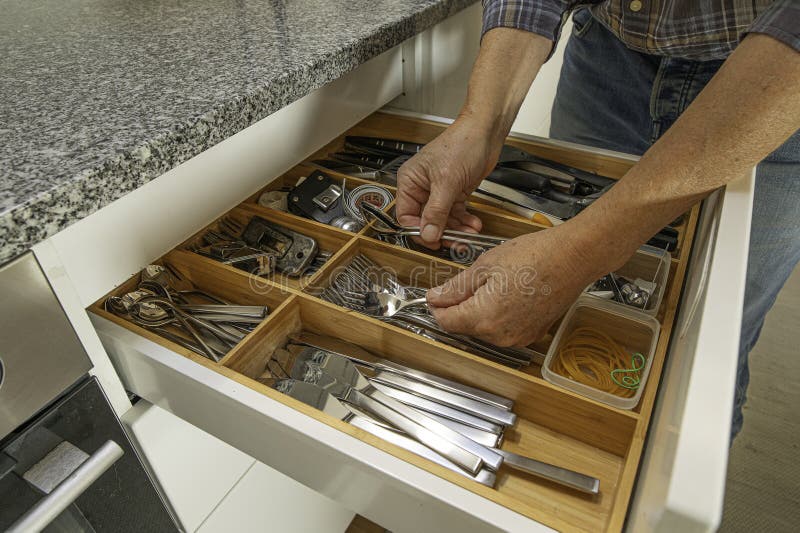 An Elderly Man is Sorting Cutlery in a Drawer in the Kitchen Stock ...