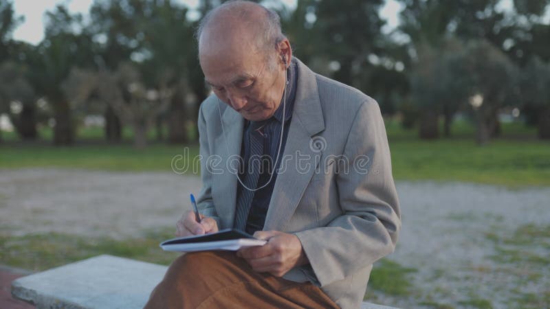 Elderly Man Writing on Notepad in Park Stock Footage - Video of calm ...