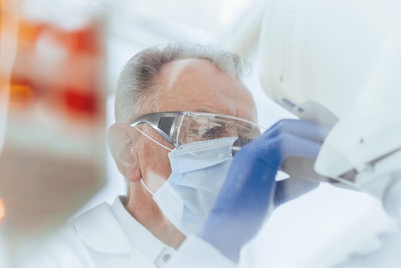 Elderly Scientist in a Protective Mask Looking through a Microscope ...