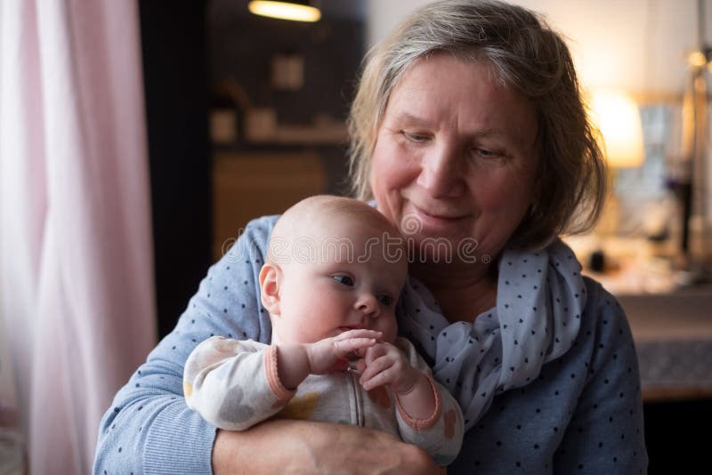 Elderly Woman Grandmother Holding A Newborn In Her Arms Stock Image