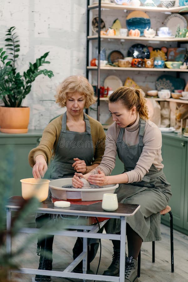 Elderly Woman Learning Pottery on Spinning Wheel with Young Instructor ...