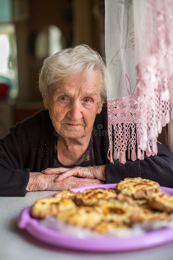 An Elderly Woman Sits at a Table with a Rustic Pastries. Happy. Stock ...
