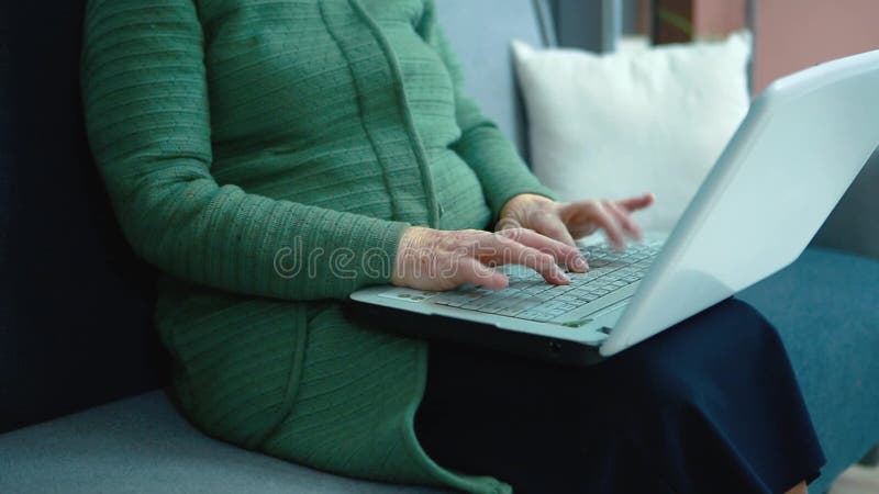 An Elderly Woman Works at a Computer Sitting on a Sofa Stock Video ...