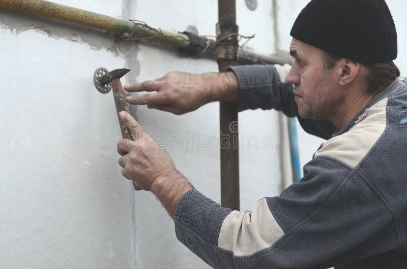 An Elderly Workman Clogs a Dowel into a Plastic Umbrella Mount in a ...