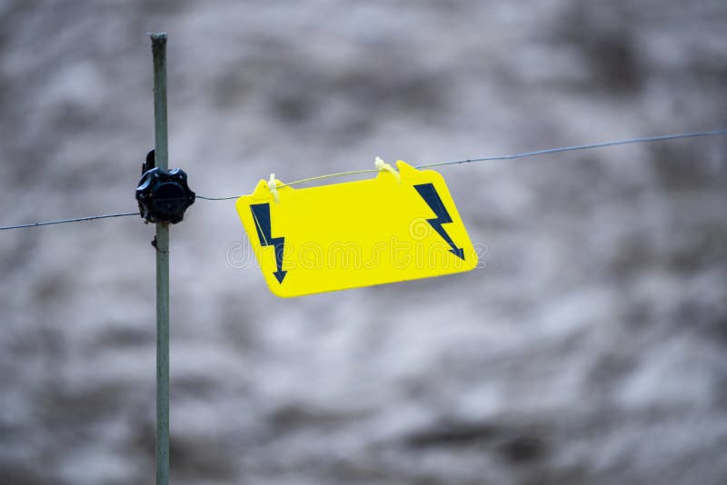 Electric Fence Warning Sign. a Yellow Warning Sign Hangs on a Wire and ...