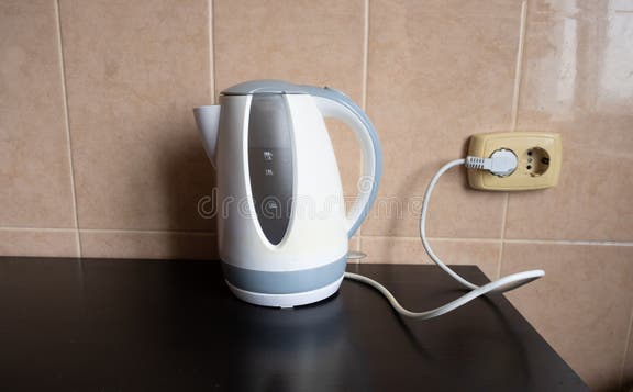 An Electric Kettle Stands on the Table in the Kitchen, Plugged into the ...