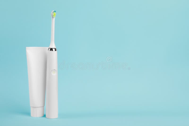 Electric Toothbrush and Toothpaste on Light Blue Background, Space for ...