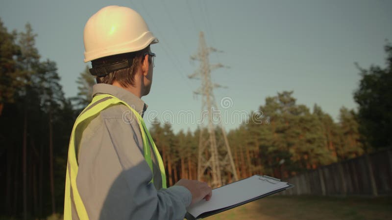 Electrical Engineer Looks at an Electrical Tower, Wearing Protective ...