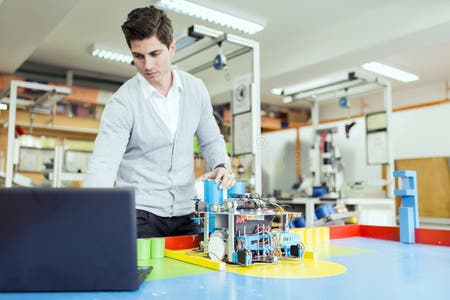 Electrical Engineer Programming a Robot during Robotics Class Stock ...