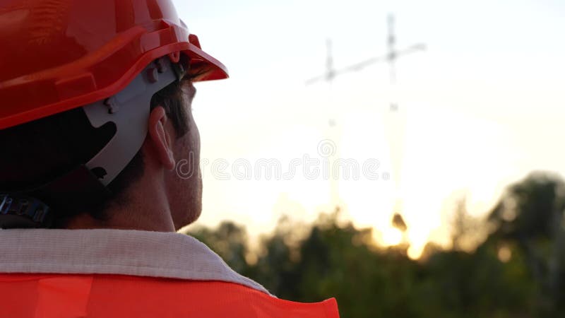 Young Engineer Standing Outdoors while Looking at the High Voltage ...