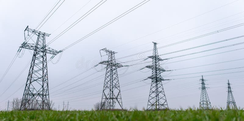 Electrical Net of Poles on a Panorama of Gray Sky and Green Meadow ...