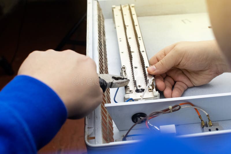 An Electrical Repairman Repairs a Con. a Close-up of an Open Heater and ...