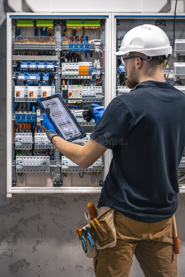 Electrical Technician Working in a Switchboard with Fuses, Uses a ...