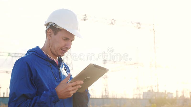 Electrical Worker Engineer a Working with Digital Tablet, Near Tower ...
