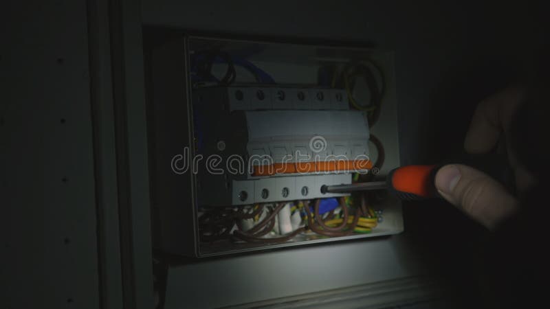 Electrician Assembles Electrical Panel in Dark by Light of Flashlight ...