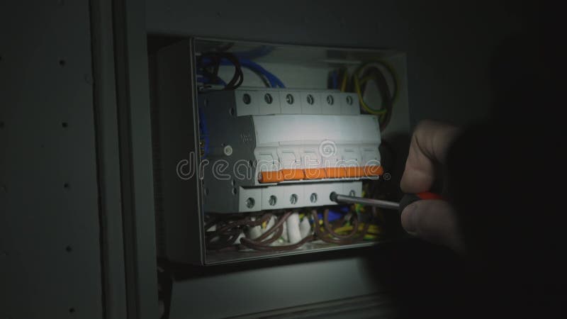 Electrician Assembles Electrical Panel in Dark by Light of Flashlight ...