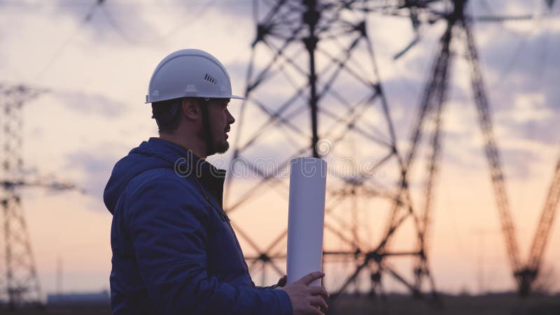 An Electrician on the Background of High Towers of Power Plants Looks ...