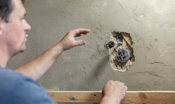 Electrician Carefully Positioning a New Electrical Socket into a ...