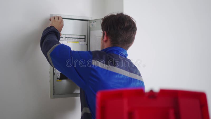 Electrician Inspecting Electrical Fuse Box. Master in Uniform Screwing ...