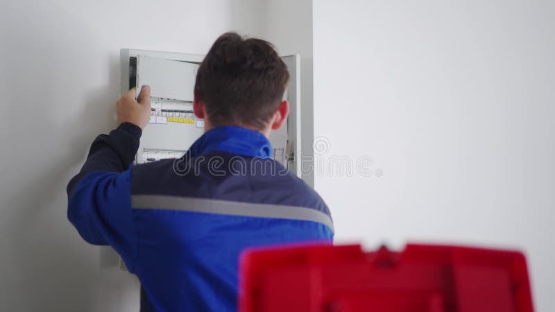 Electrician Assembles Electrical Fuse Box. Master in Uniform Puts on ...