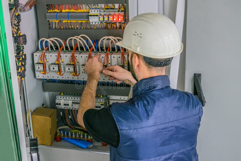 A Qualified Engineer Works in an Electrical Panel. Worker Repairs High ...