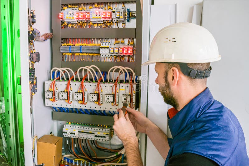 A Qualified Engineer Works in an Electrical Panel. Worker Repairs High ...